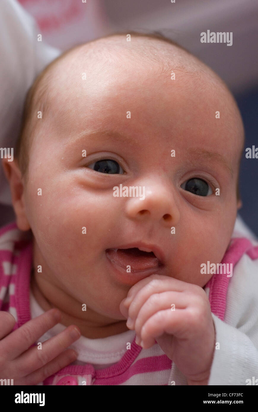 Female two month old baby dressed in a white and pink striped dress a ...