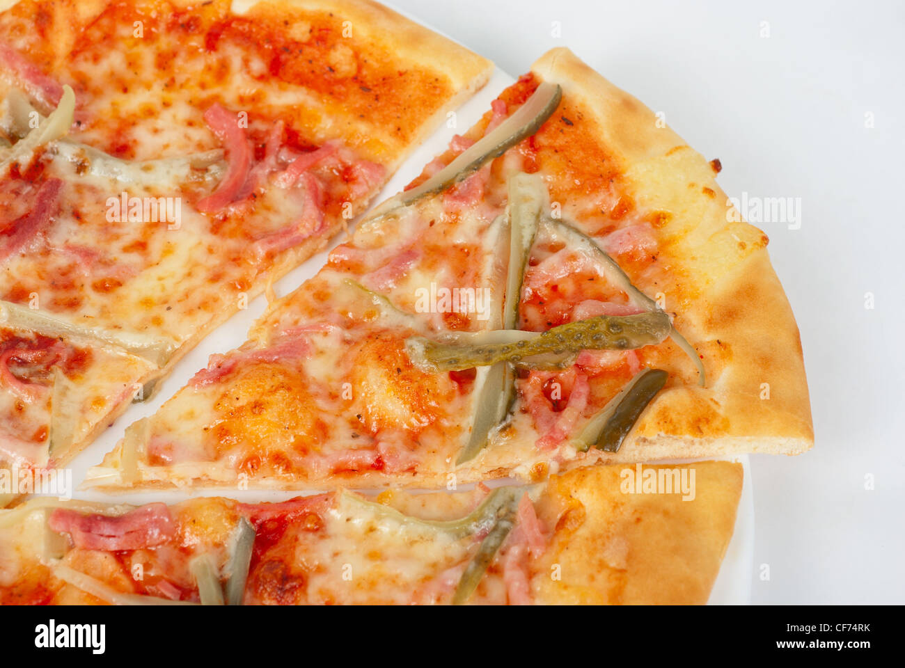 pizza closeup with boiled sausage, ham, marinated gherkin and ...
