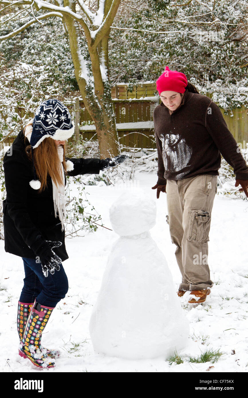 Young man and woman building a snowman Stock Photo - Alamy