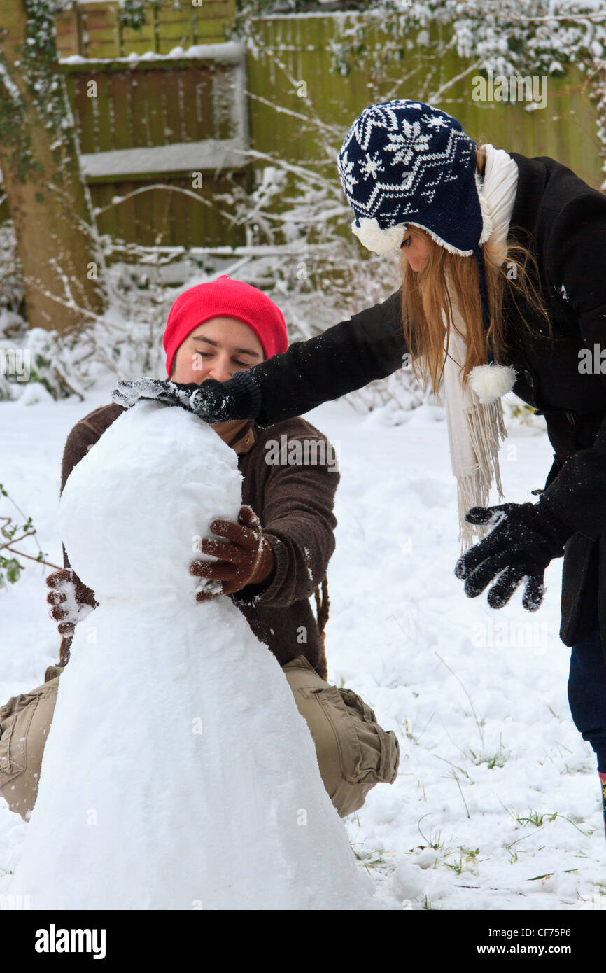 Young man and woman building a snowman Stock Photo - Alamy