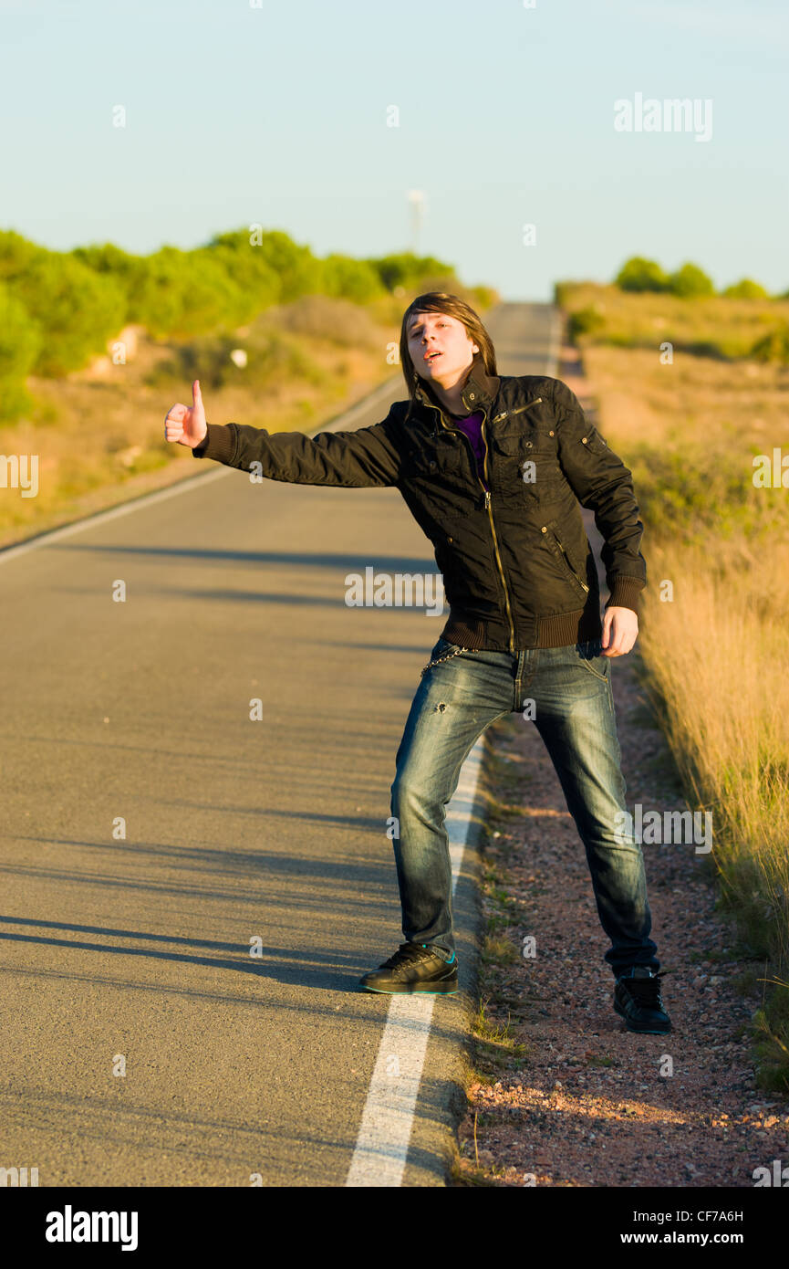 Hitchhiking youngster quite desperate to get a lift Stock Photo - Alamy