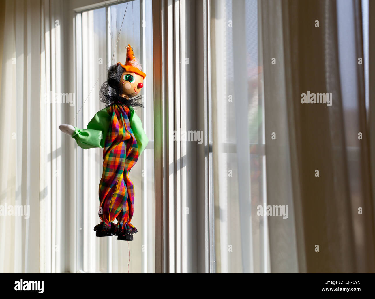 Puppet or marionette hanging in window and gazing outside into sunlit ...