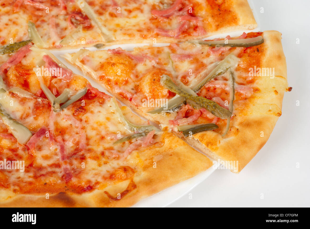 pizza closeup with boiled sausage, ham, marinated gherkin and ...