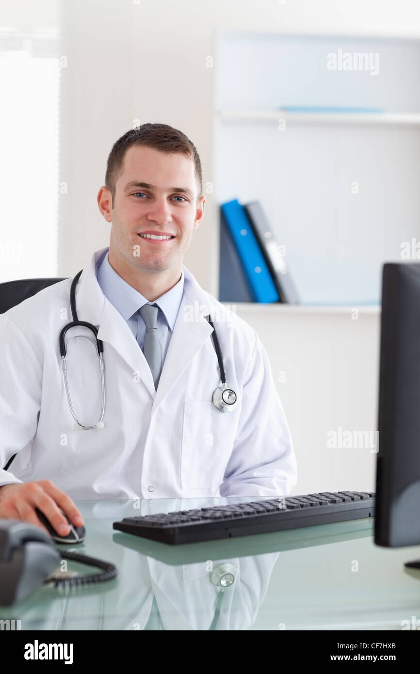 Smiling doctor sitting on his computer Stock Photo - Alamy