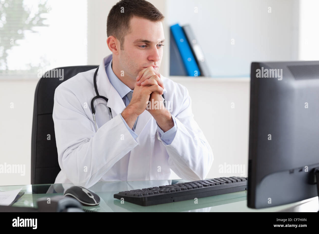 Thinking doctor looking at his screen Stock Photo - Alamy