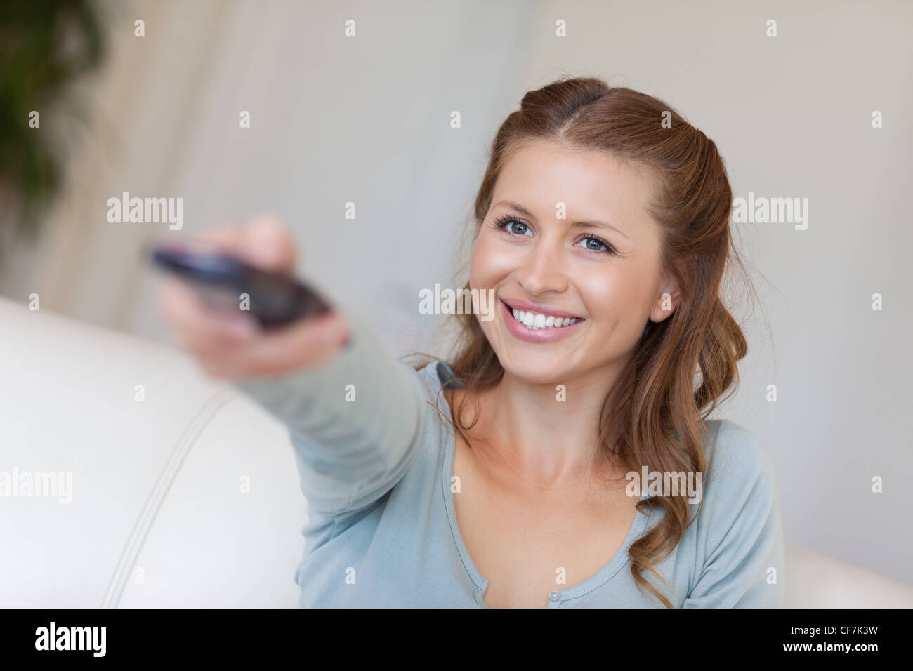 Smiling woman watching tv on her couch Stock Photo - Alamy
