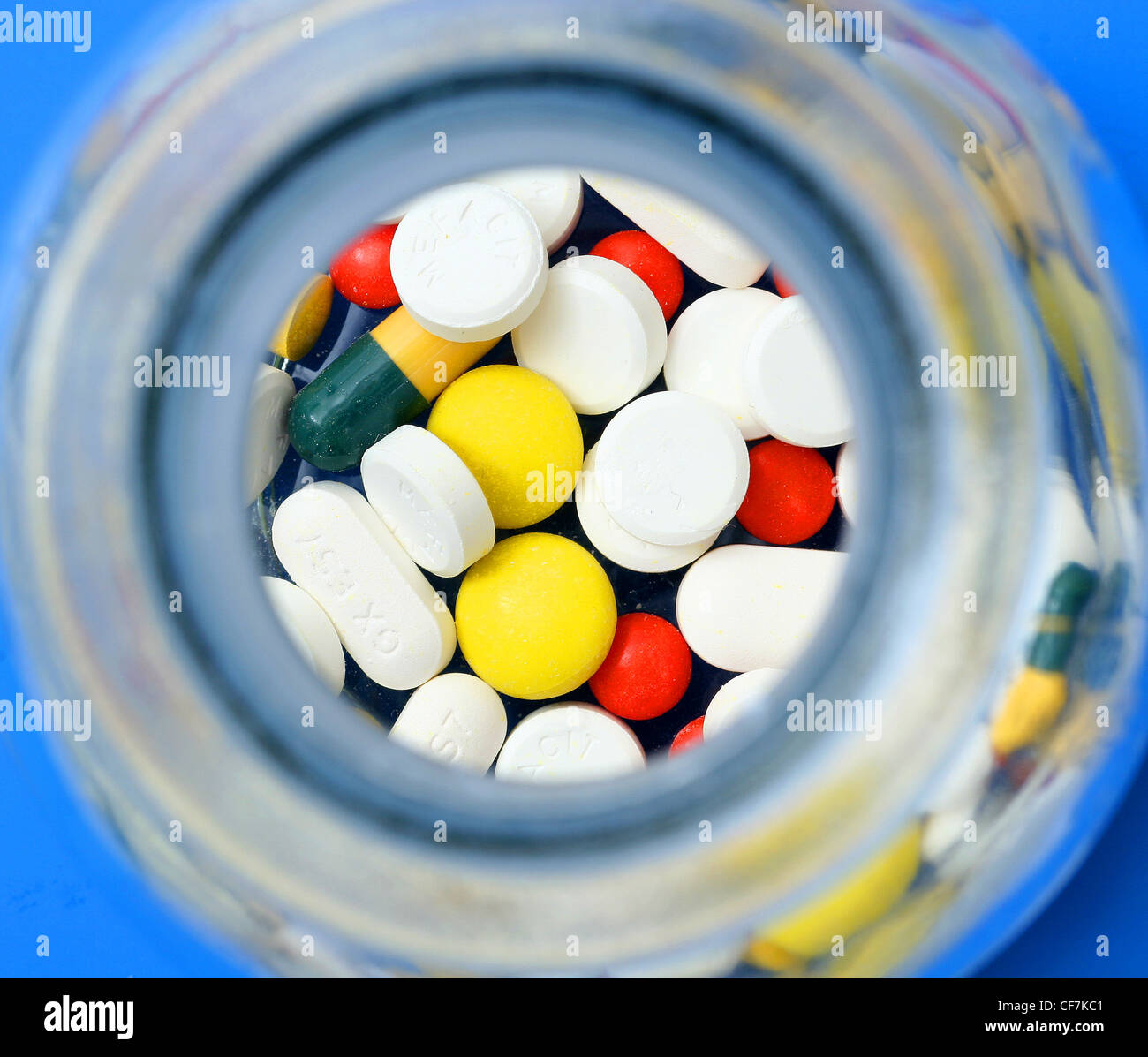 A glass bottle of round white tablets, round yellow tablets, round red ...
