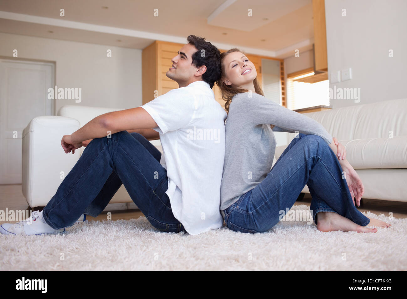 Side view of couple sitting on the floor back-to-back Stock Photo - Alamy