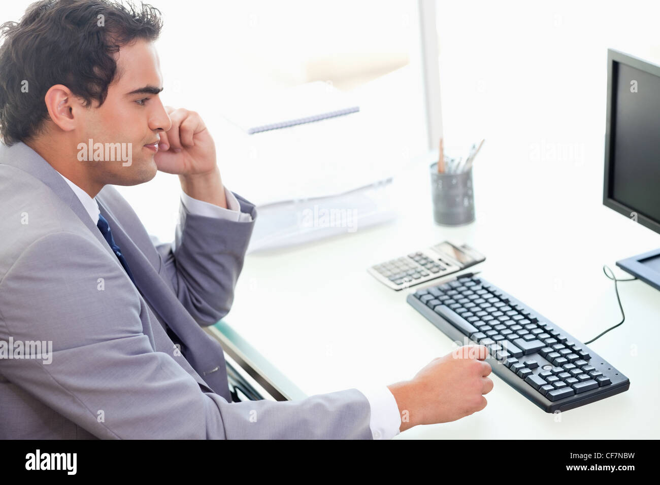 Side view of businessman sitting at his desk Stock Photo - Alamy