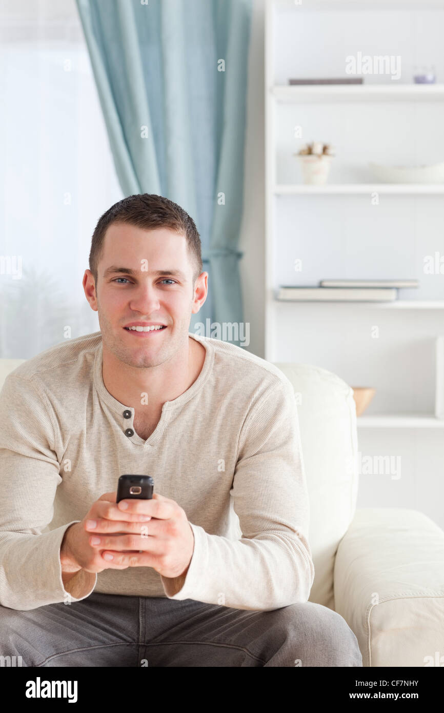 Portrait of a man sending text messages while sitting on a sofa Stock ...