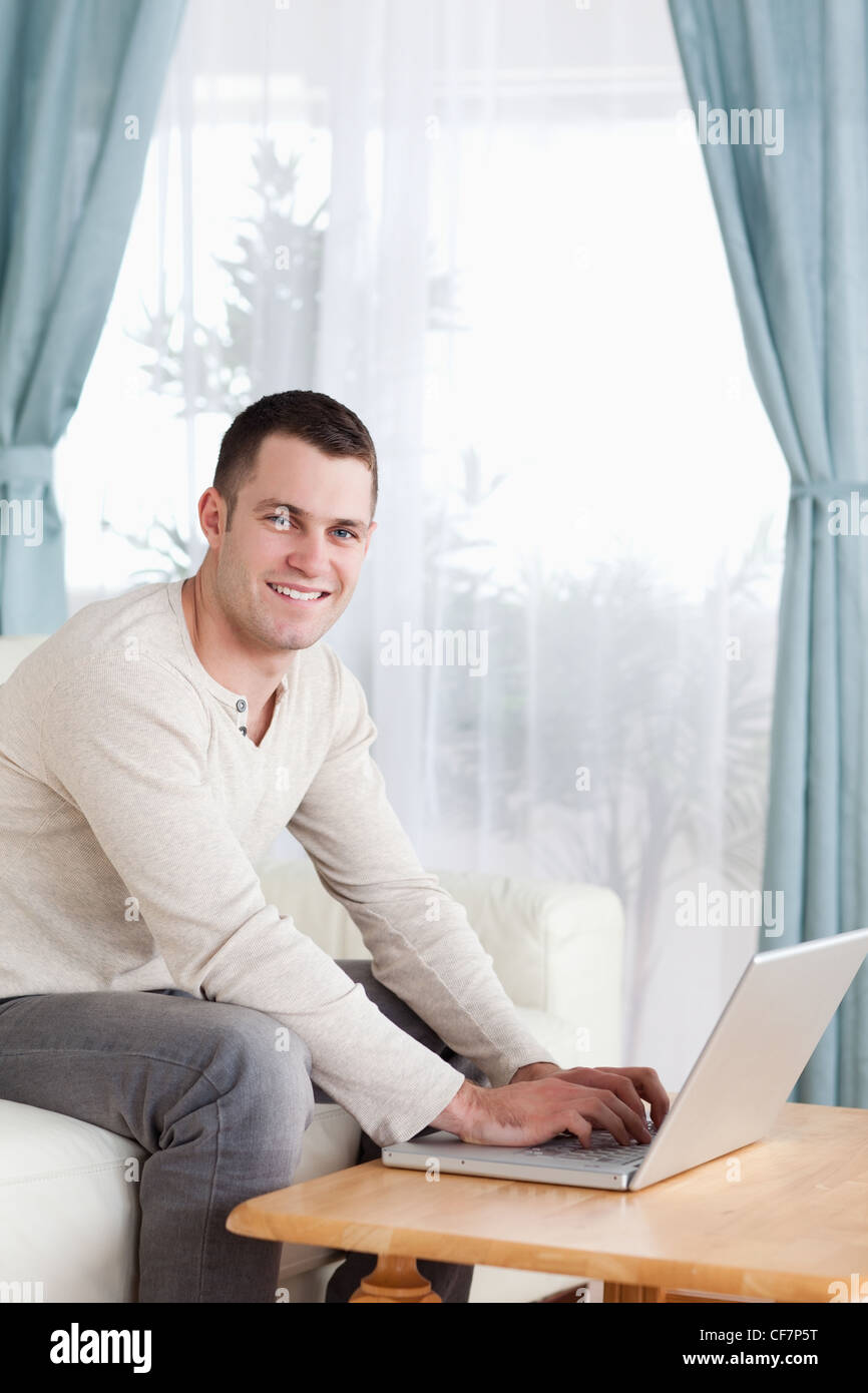 Portrait of a smiling man typing on his laptop Stock Photo - Alamy
