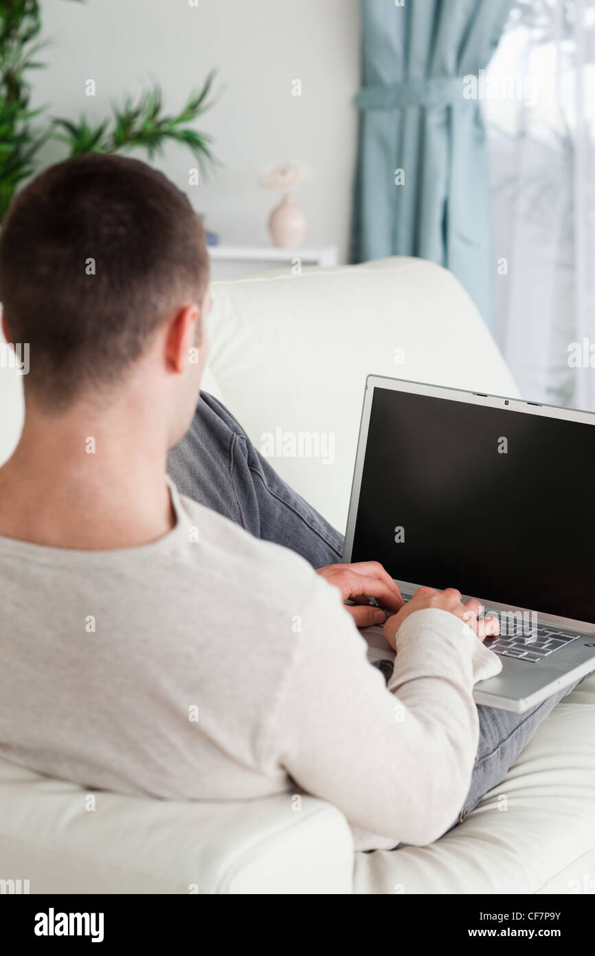 Portrait of a man lying on his couch to use a laptop Stock Photo - Alamy