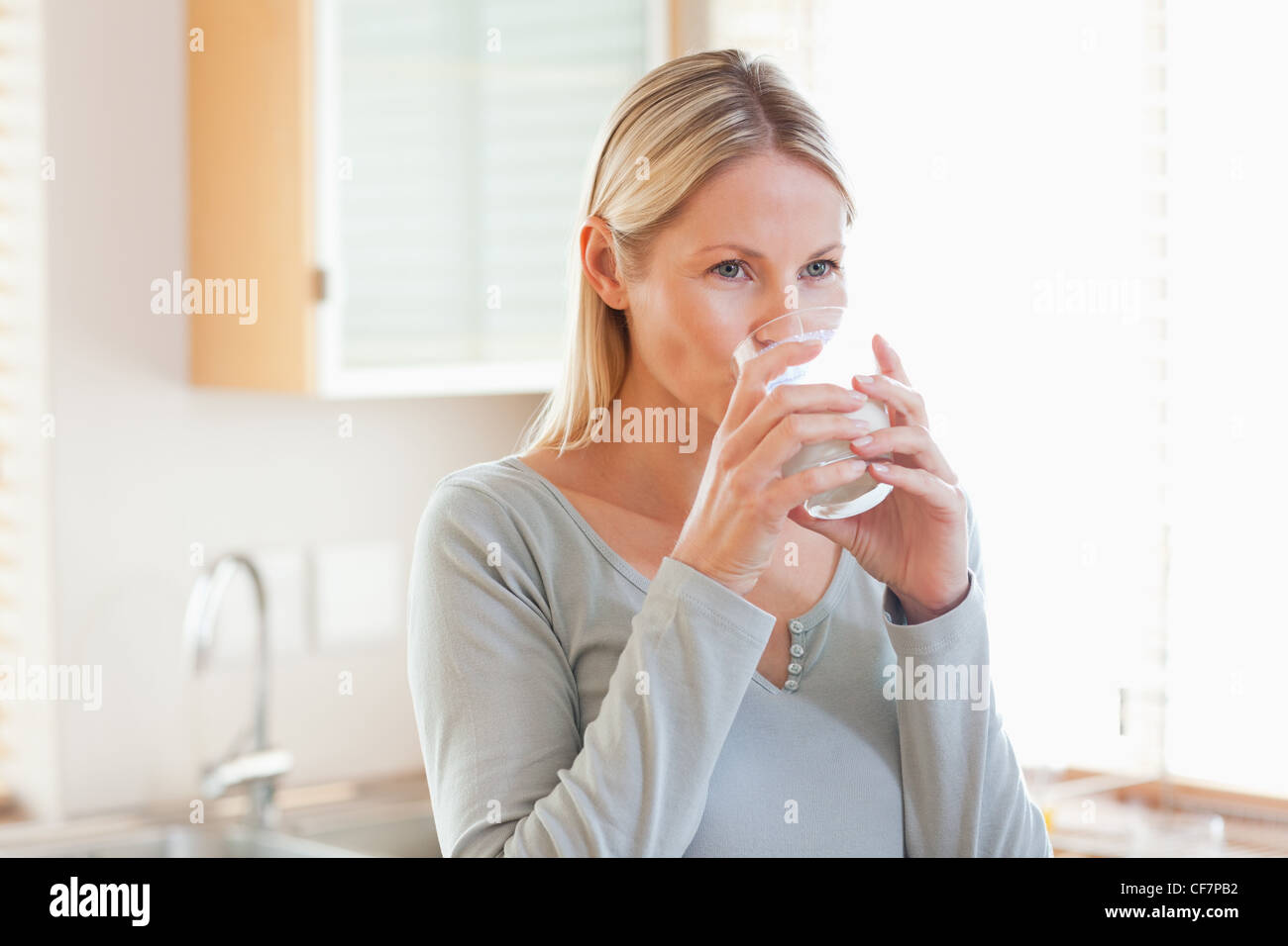 Woman in the kitchen drinking water Stock Photo - Alamy