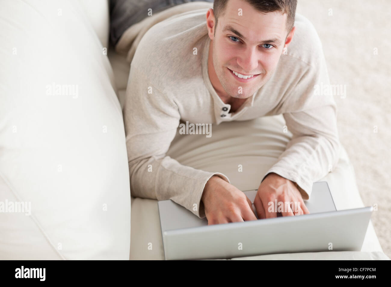 Happy man lying on a couch with a notebook Stock Photo - Alamy
