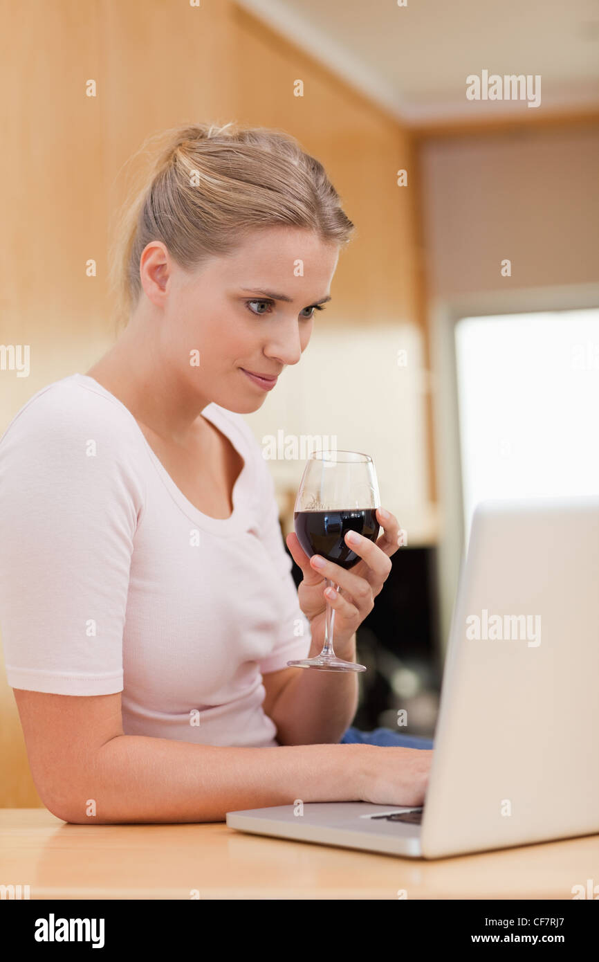 Portrait of a woman using a laptop while drinking wine Stock Photo - Alamy