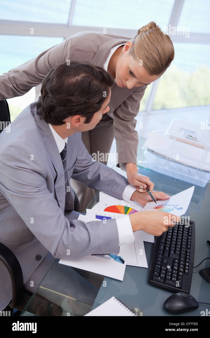 Portrait of a manager pointing at something to her secretary on a graph ...
