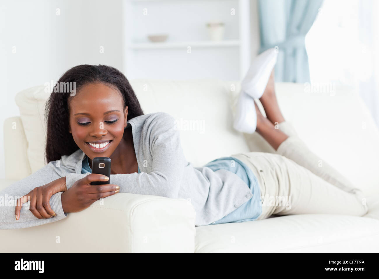 Woman texting on couch Stock Photo - Alamy