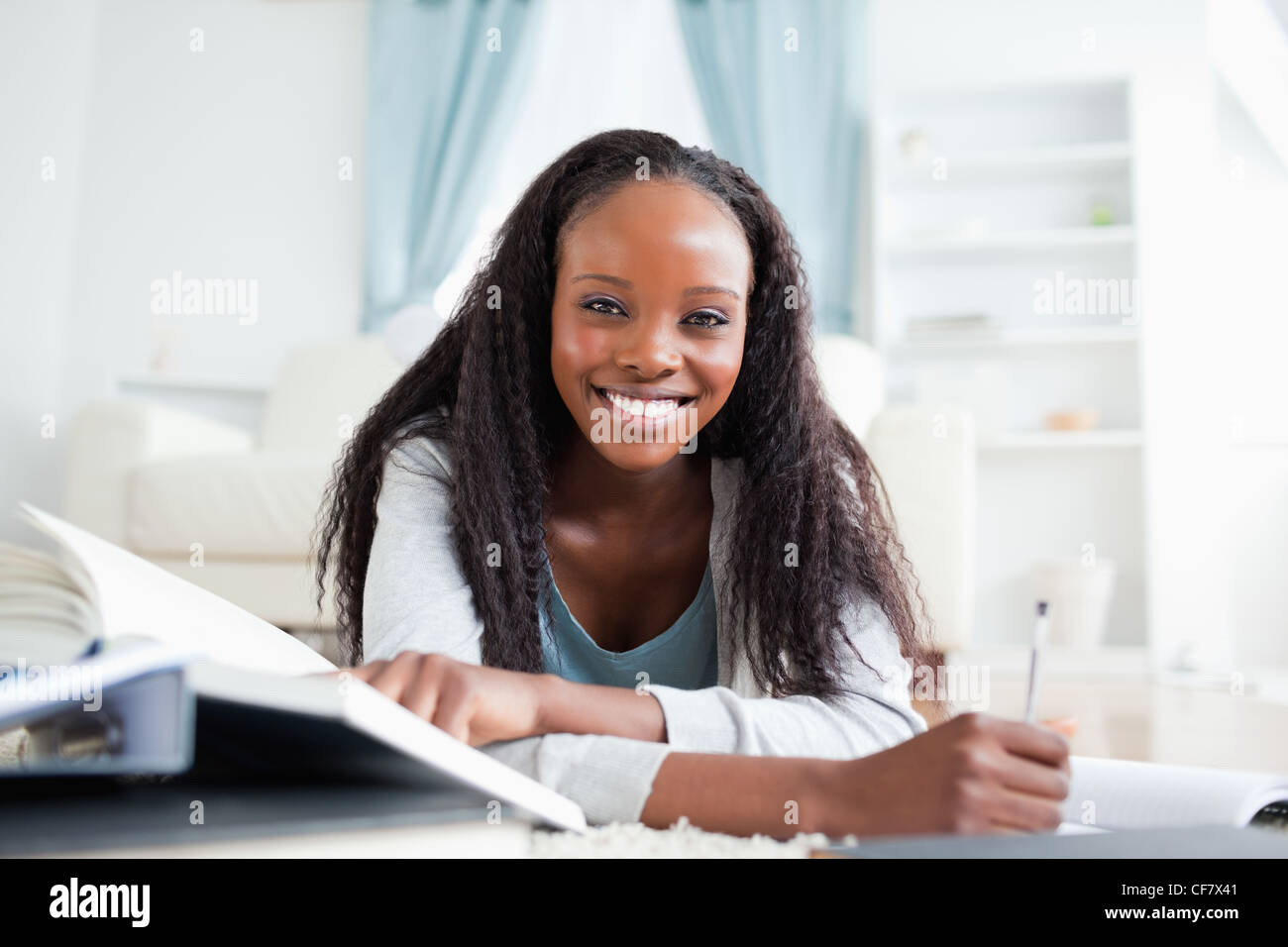 Woman lying on the carpet doing homework Stock Photo - Alamy