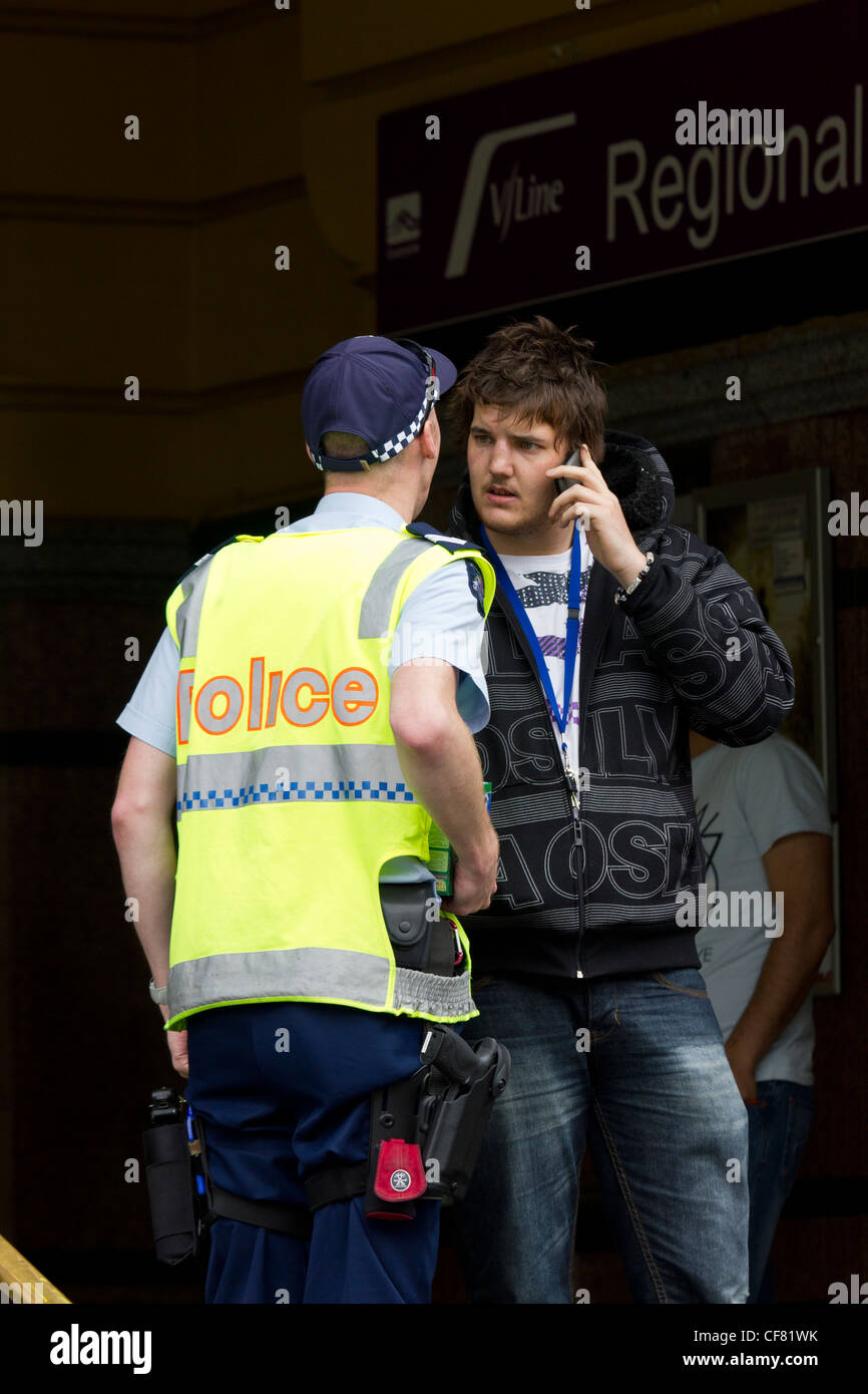 policeman talking to youth on mobile phone, Flinders Street Station ...