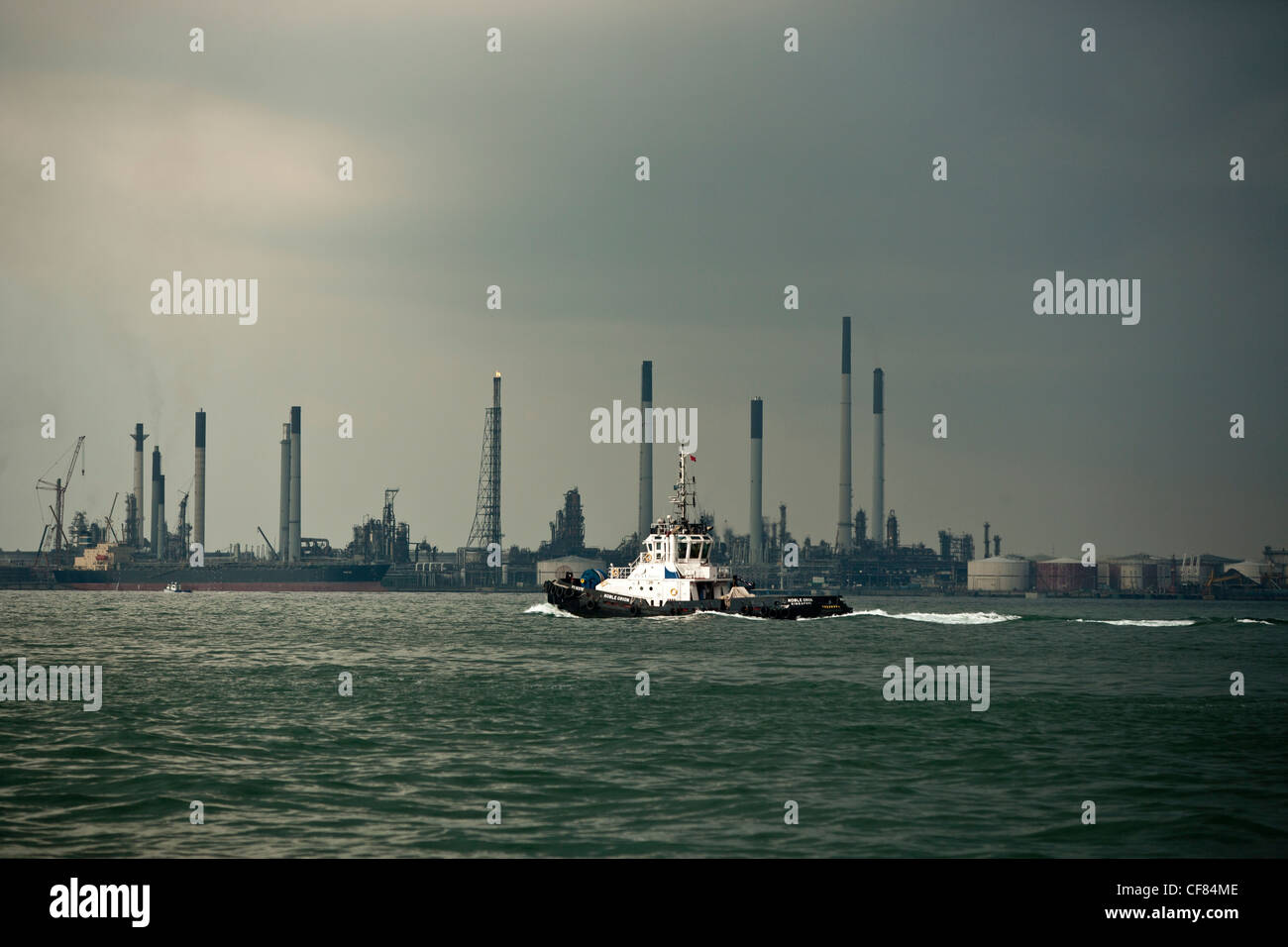 A tug boat passes in front of an offshore oil refinery in Singapore ...