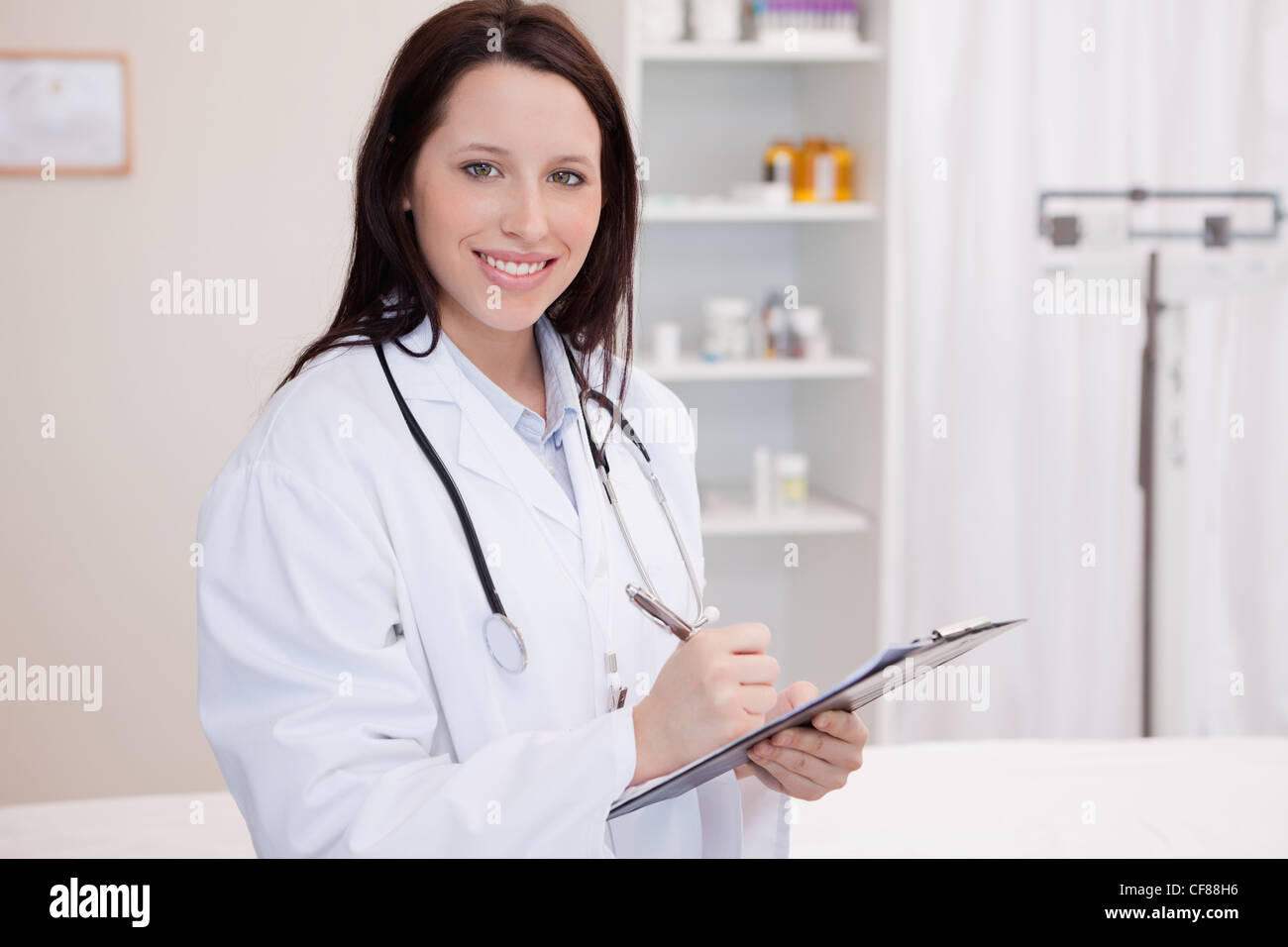 Smiling female physician taking notes Stock Photo - Alamy