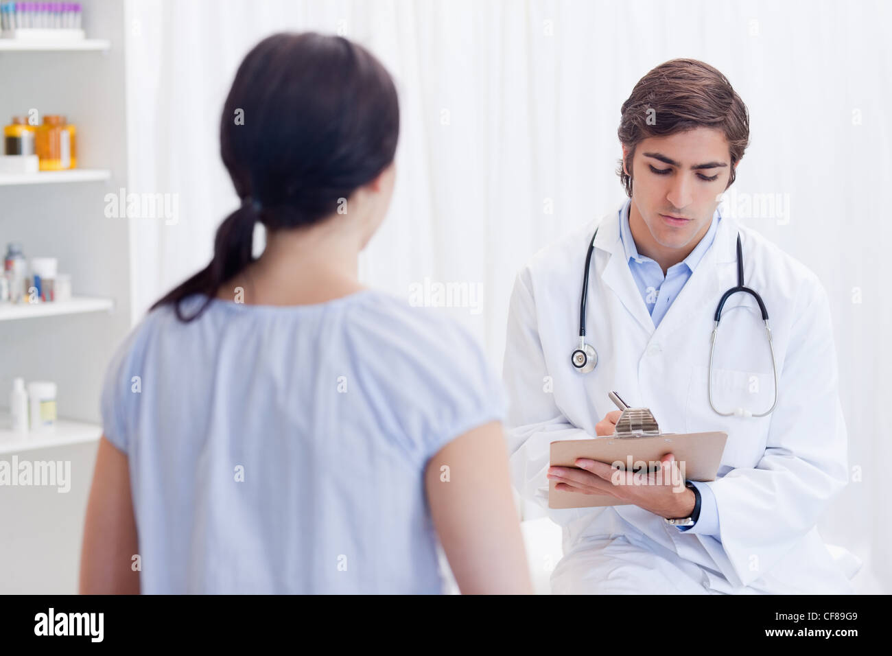 Physician taking notes while patient is talking Stock Photo - Alamy