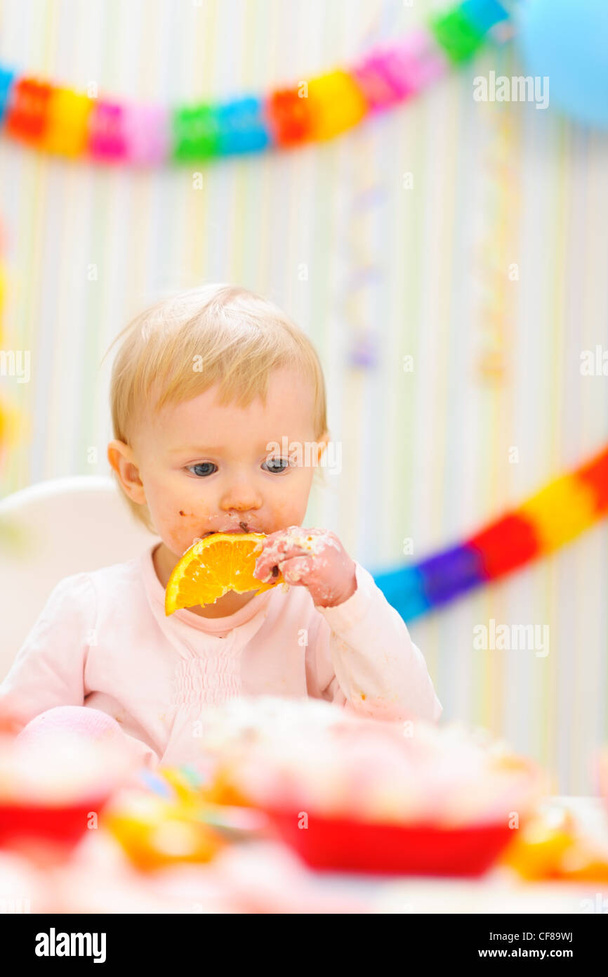 Baby eating orange on first birthday celebration party Stock Photo - Alamy