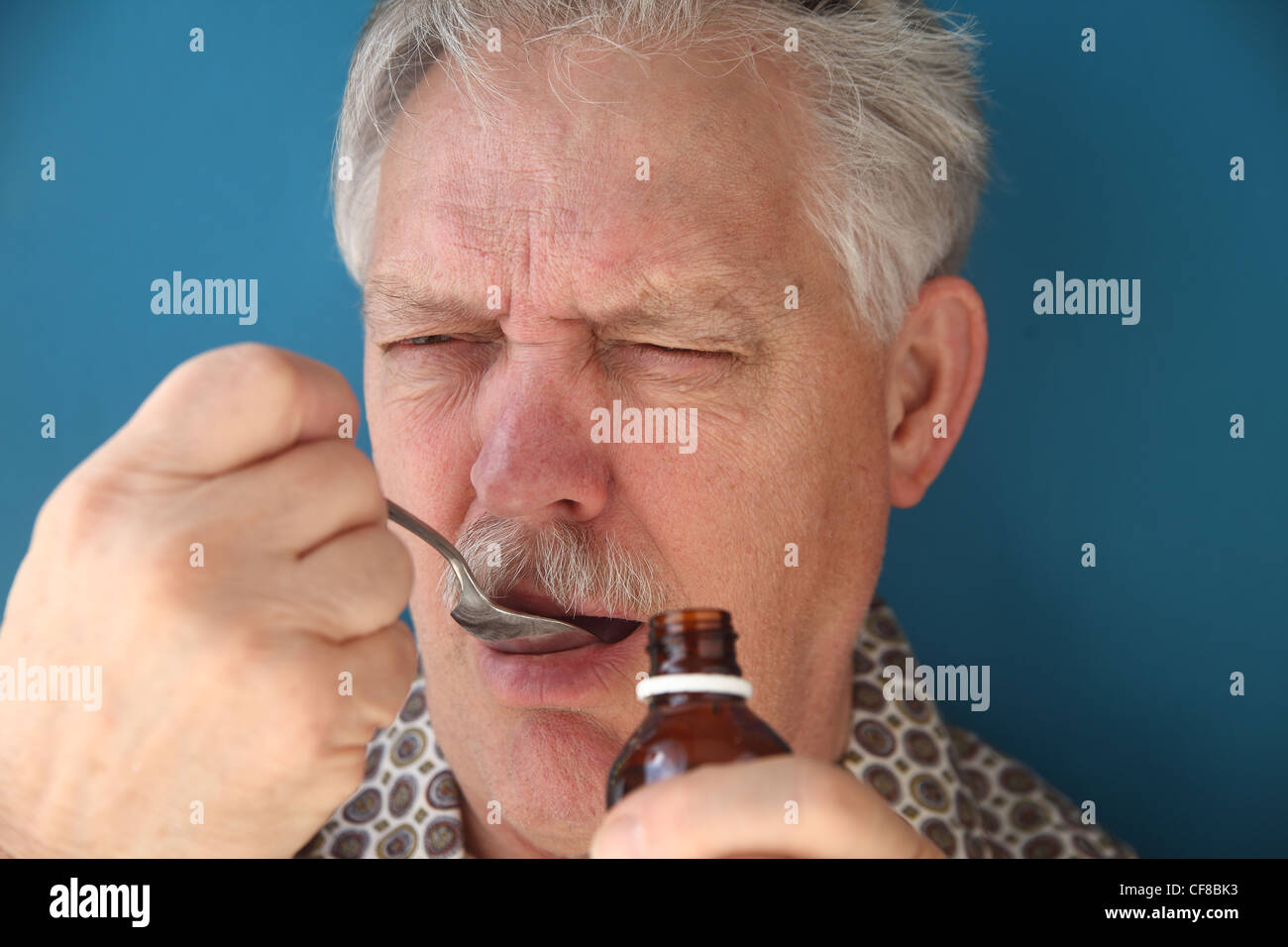 sick man frowns as he takes a spoonful of cough syrup Stock Photo - Alamy