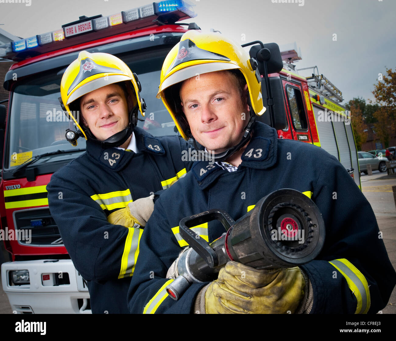 Two firemen with hose and tender Stock Photo - Alamy