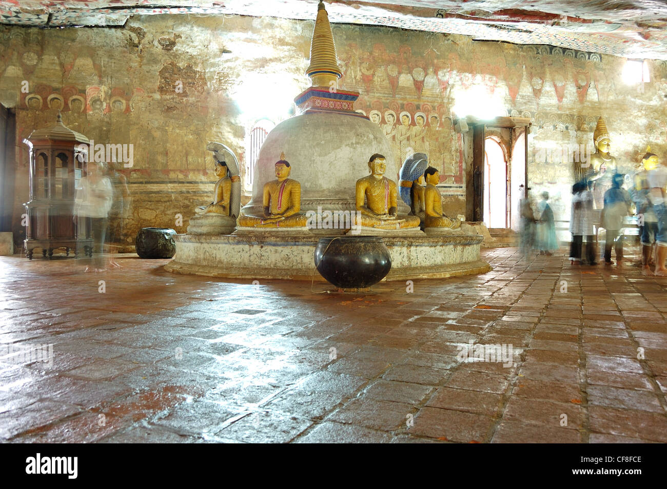 Ancient statues of Buddha around small stupa and painting on the walls ...