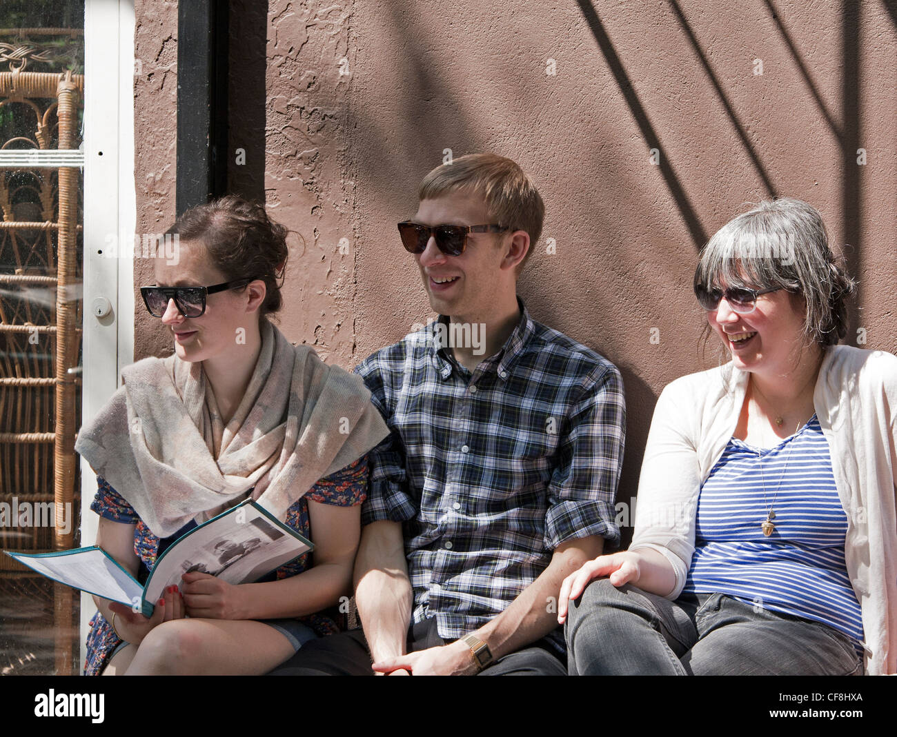 Three people wait outside for a restaurant table to become available ...