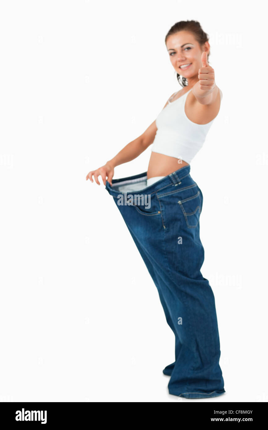 Portrait of a fit woman wearing too large pants with the thumb up Stock ...