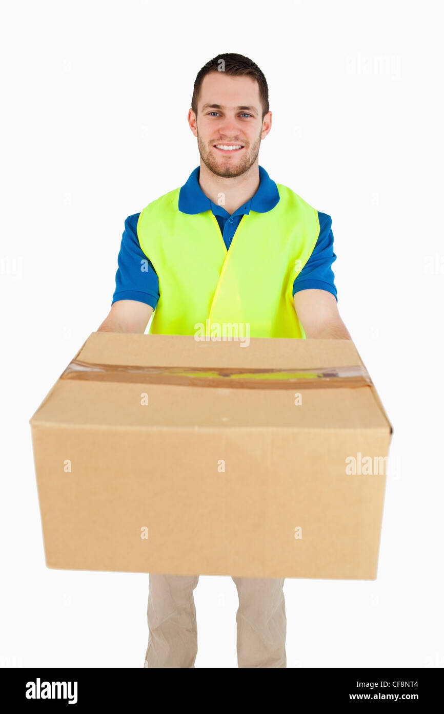 Smiling young delivery man handing over parcel Stock Photo - Alamy