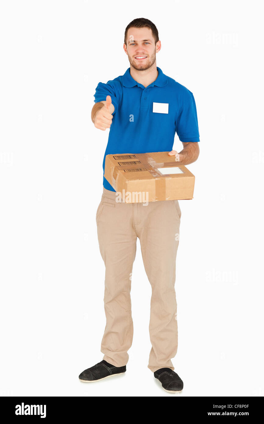 Smiling young salesman with parcel giving thumb up Stock Photo - Alamy