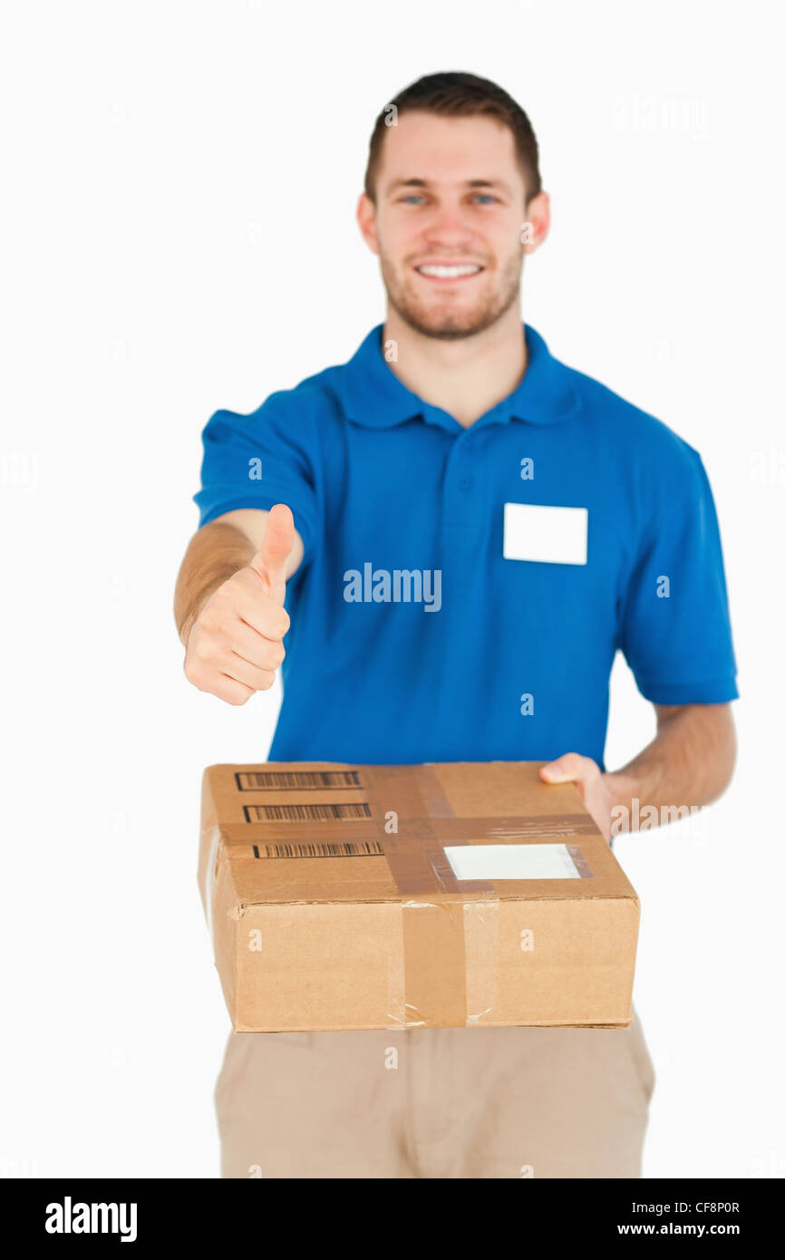Parcel handed over by smiling young salesman giving thumb up Stock ...