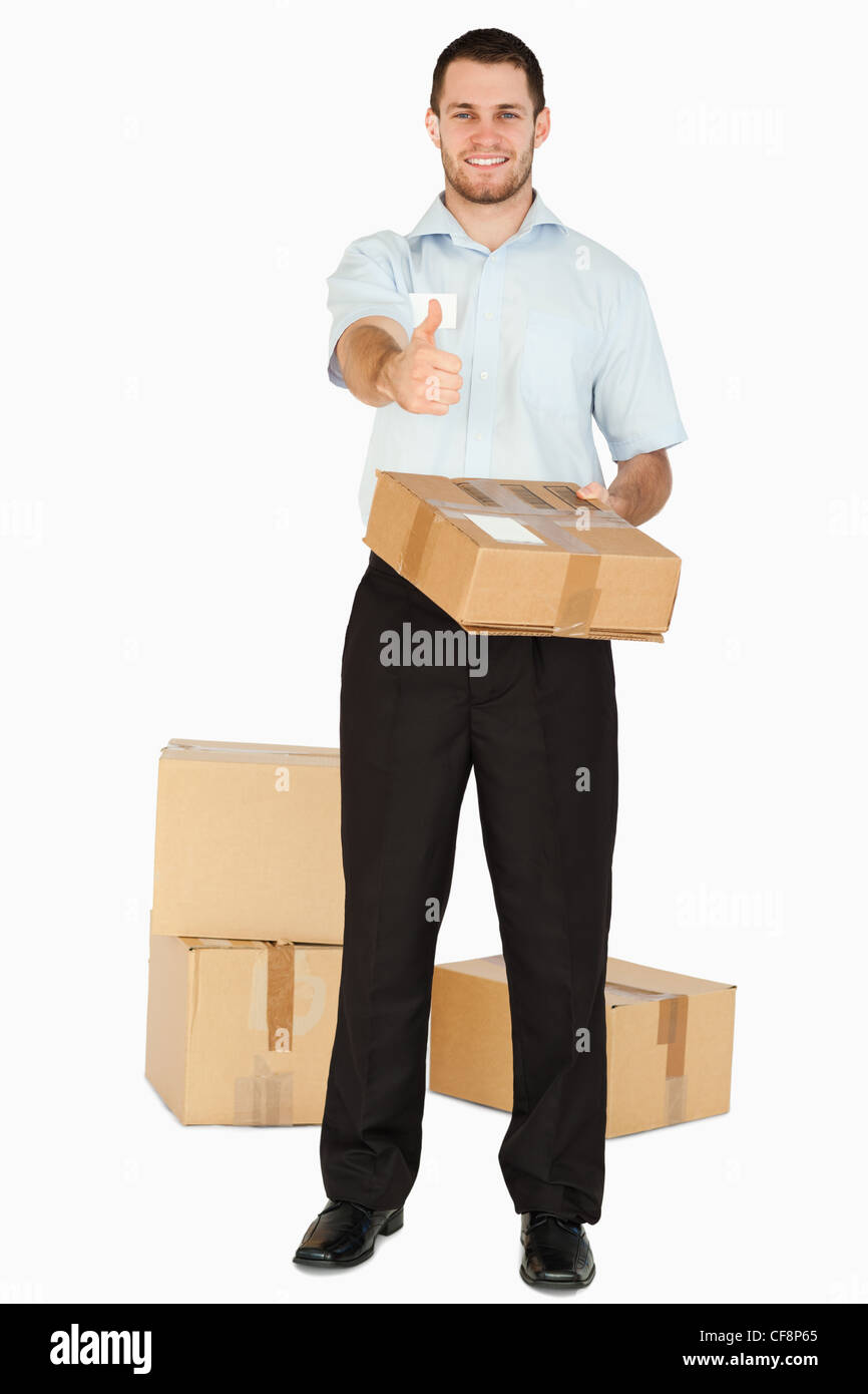 Smiling young post employee with parcels giving thumb up Stock Photo ...