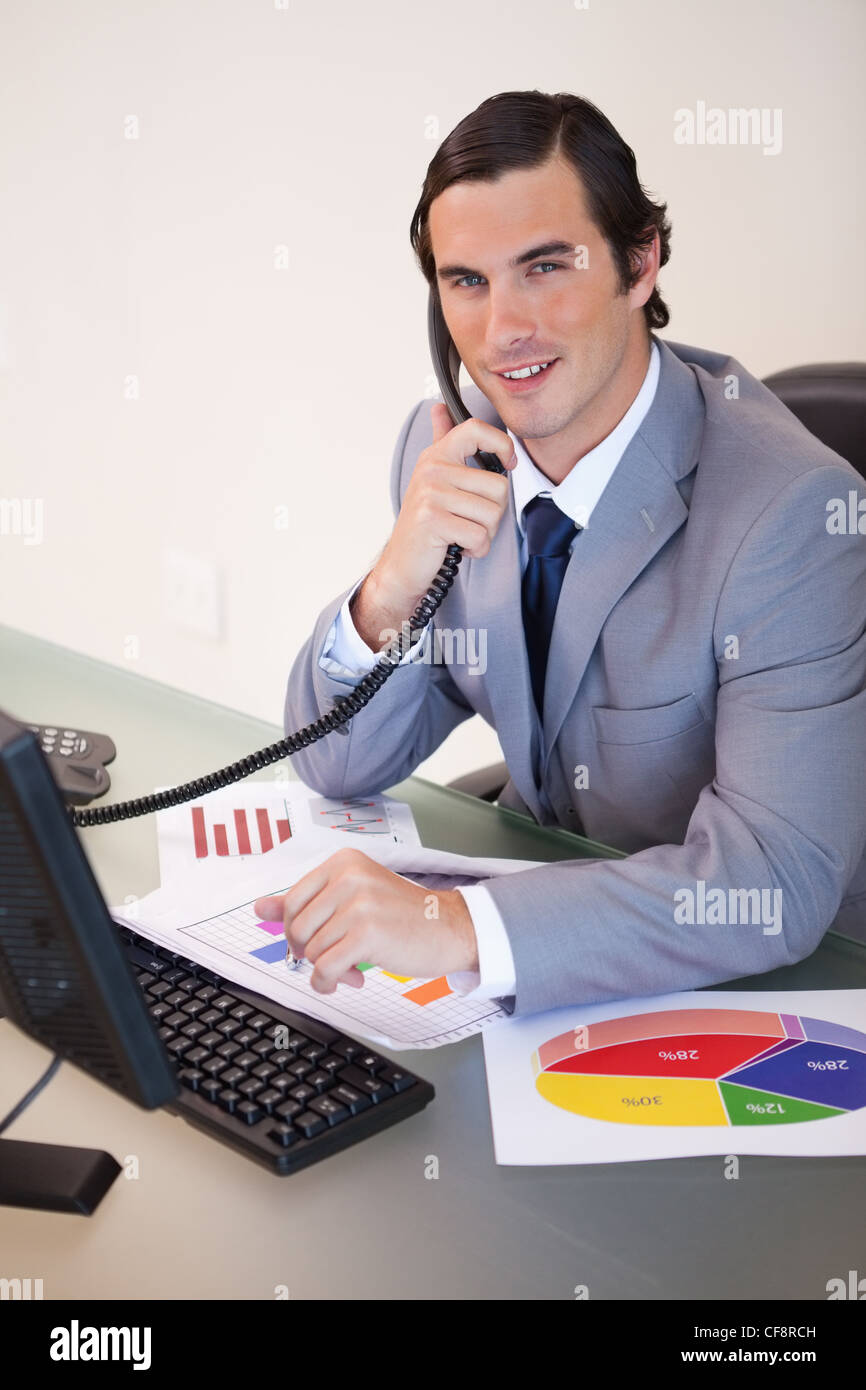 Smiling businessman on the phone working on statistics Stock Photo - Alamy