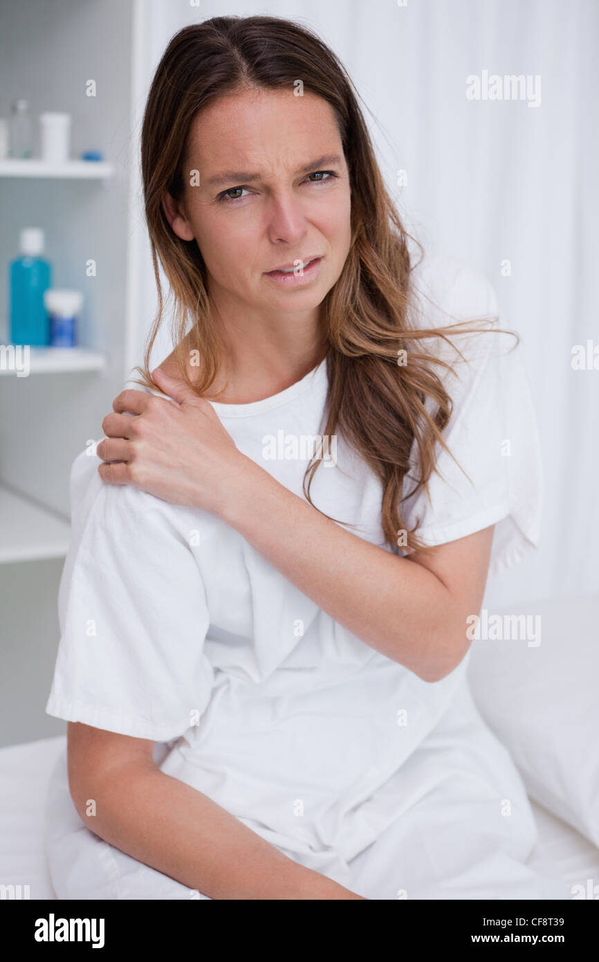 Woman covering painful shoulder Stock Photo - Alamy