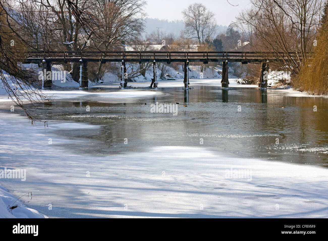 Partly frozen river with old wooden bridge in background Stock Photo ...
