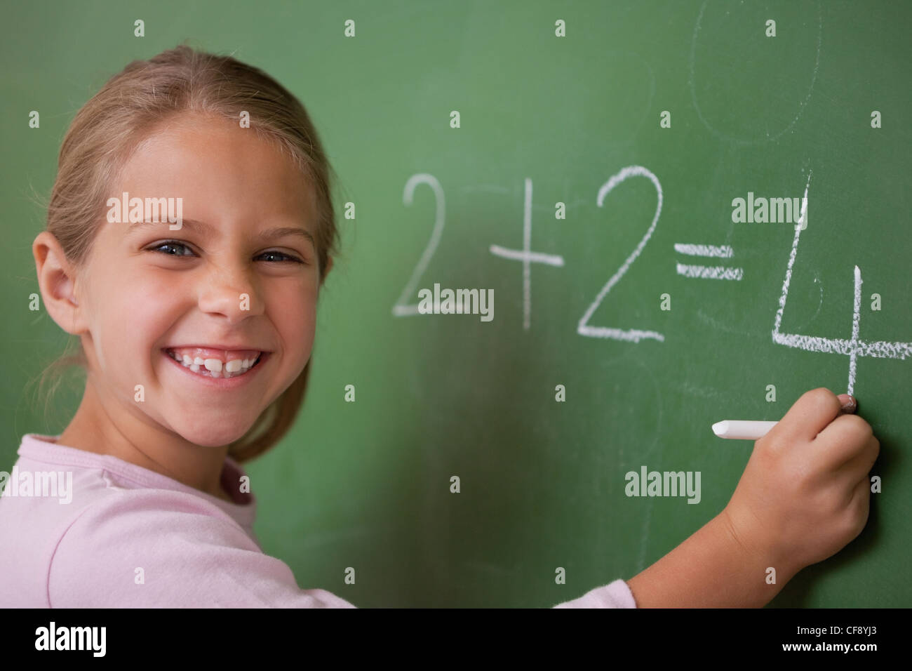 Happy schoolgirl writing a number Stock Photo - Alamy