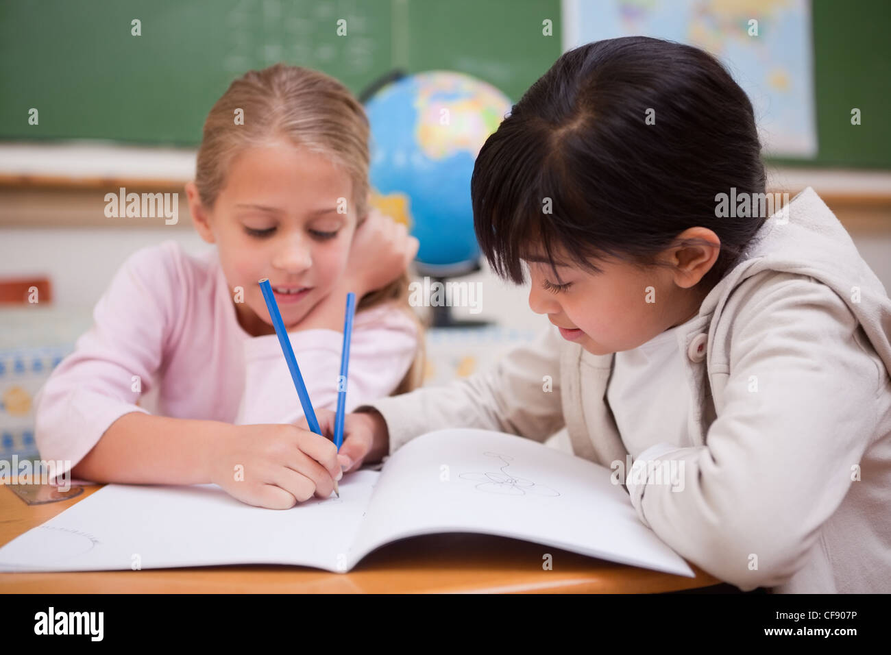 Happy schoolgirls doing classwork Stock Photo - Alamy