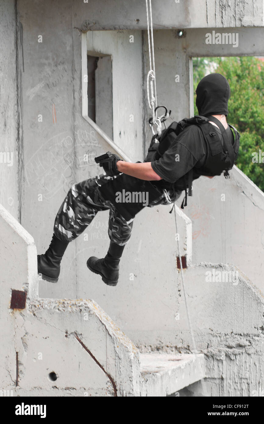 Military man in combat equipment does rappelling while assault on the ...