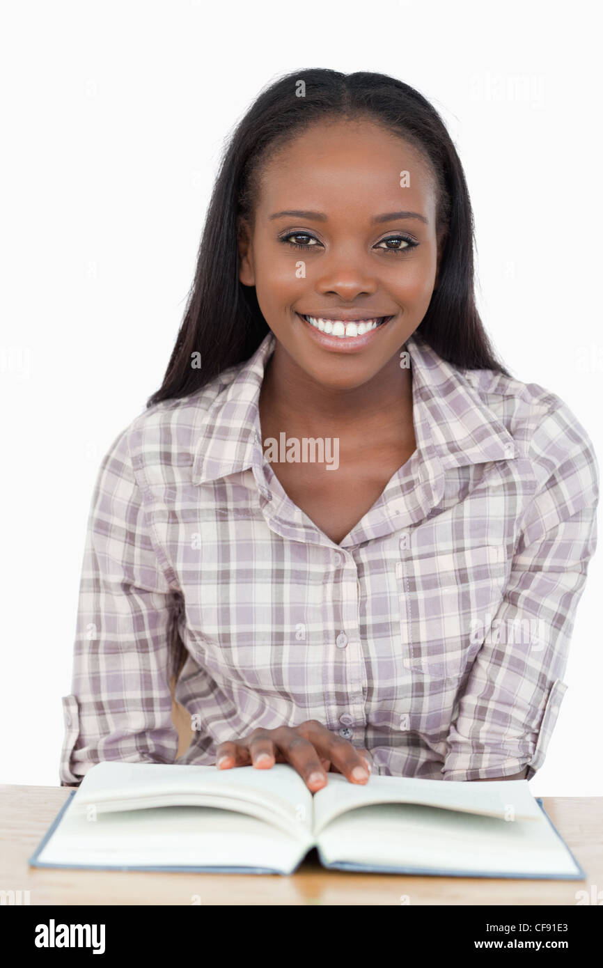 Young woman sitting behind the table reading a book Stock Photo - Alamy