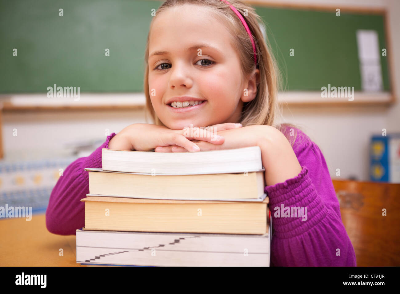 Happy schoolgirl posing with a stack of books Stock Photo - Alamy