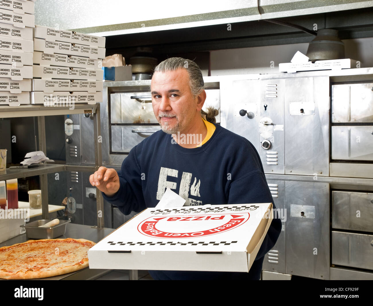 Pizza Man with boxed pizza in front of pizza oven Stock Photo - Alamy