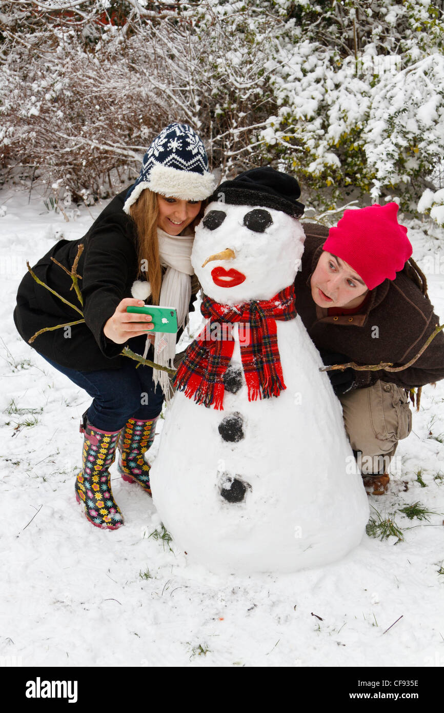 Young man and woman building a snowman Stock Photo - Alamy