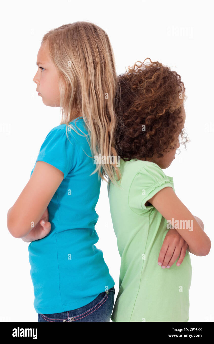 Portrait of unhappy girls standing back to back Stock Photo - Alamy