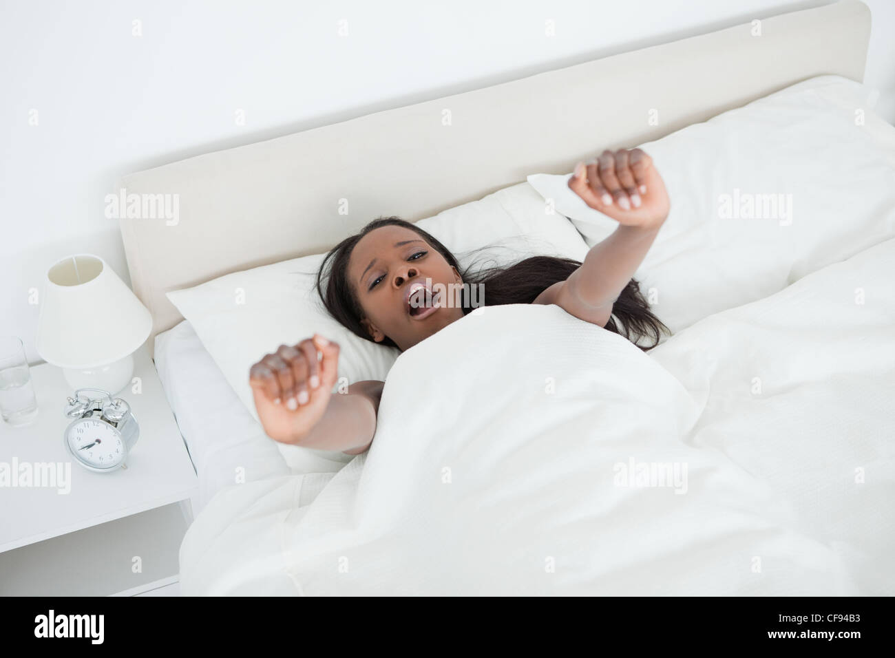 Young woman yawning and stretching her arms while waking up Stock Photo ...