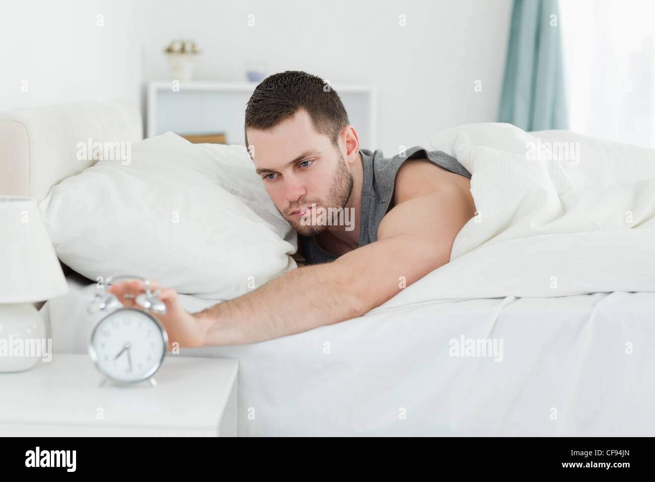 Tired man being awakened by an alarm clock Stock Photo - Alamy
