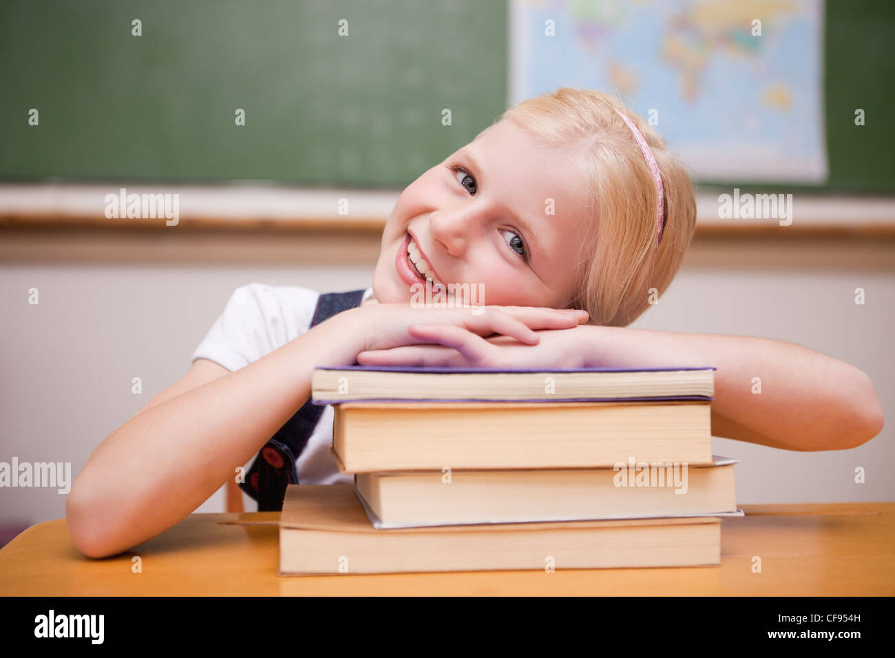 Smiling girl leaning on books Stock Photo - Alamy